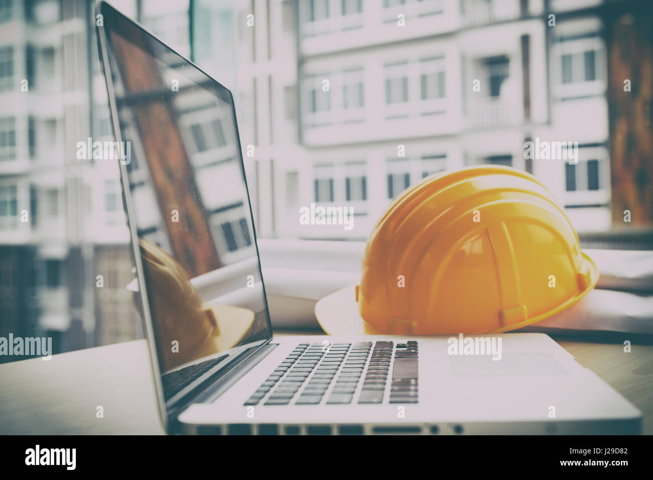 engineer desk with laptop computer, orange helmet, blueprint roll with ...