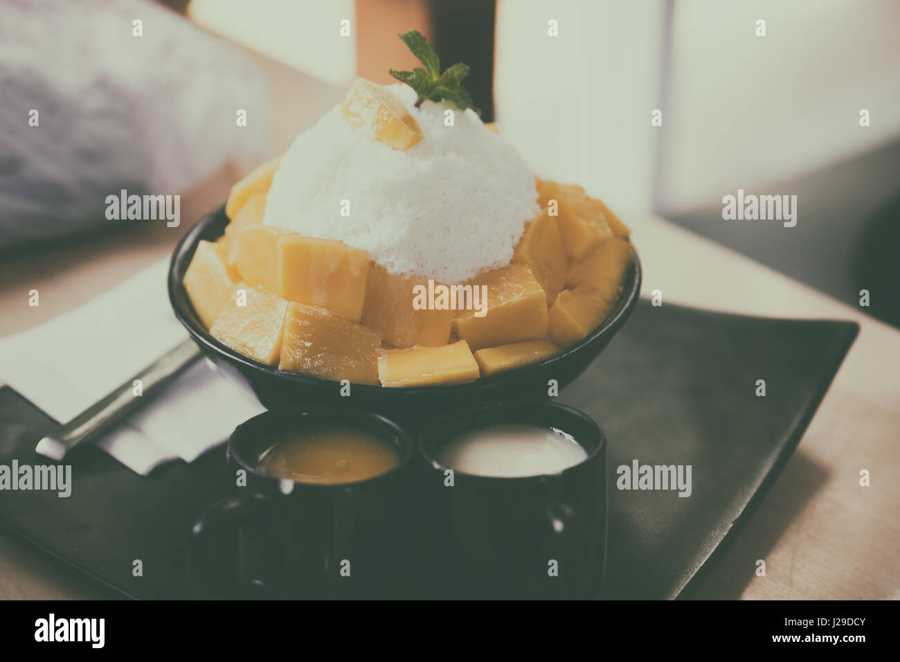 Shaved Ice with Fresh Mango dessert on Black plate serving with mango ...