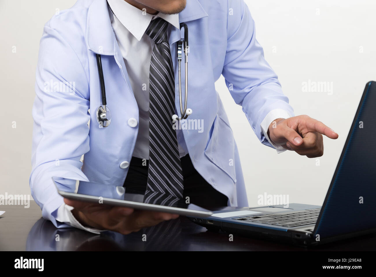 Male doctor working with modern digital tablet or touchpad and pointing ...