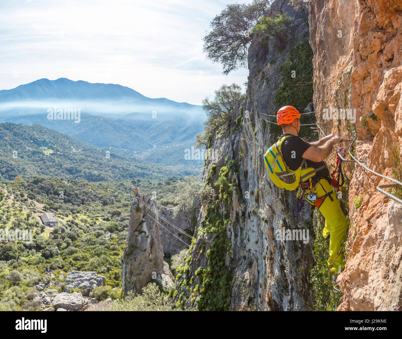 Male climber in special outfit climbing cliff with mountaineering ...