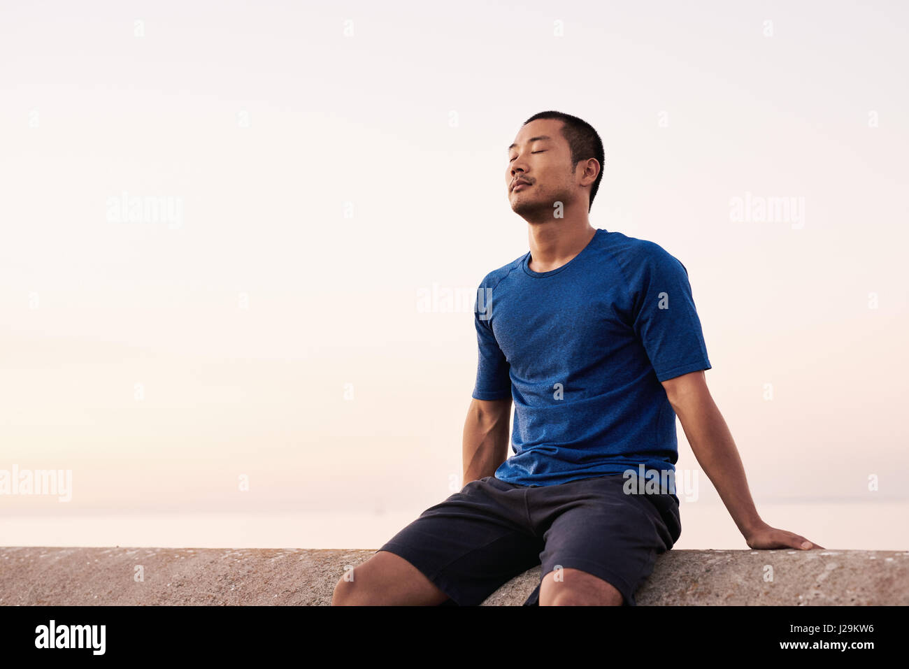 Athletic Asian man taking a breather during a morning run Stock Photo ...