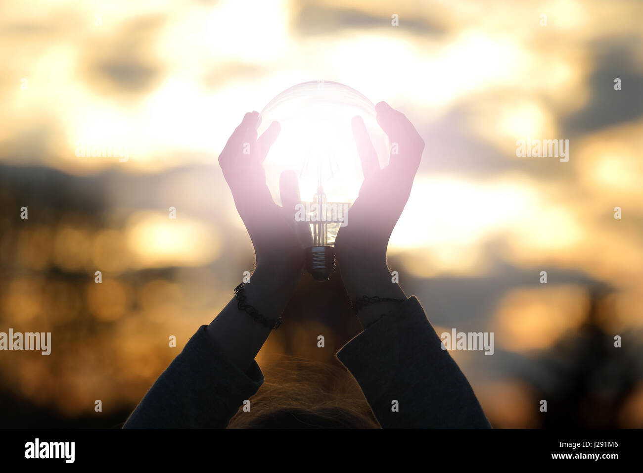 Energy light bulb from sunset on hand concept Stock Photo - Alamy