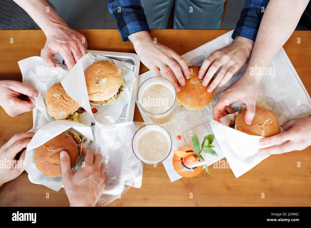 Group of friends toasting beer glasses and eating at fast food - Happy ...