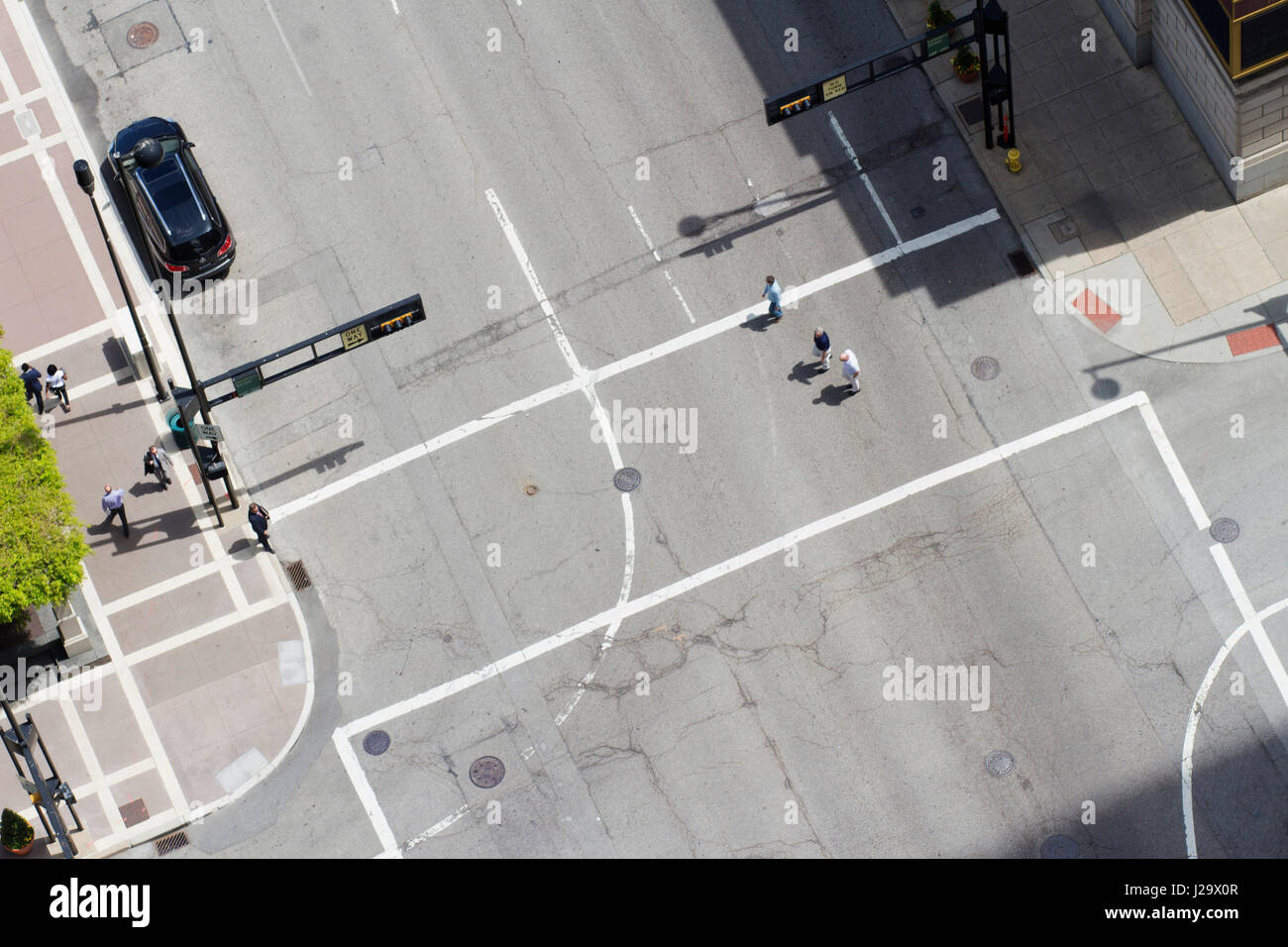 Street corner view from above with people walking across a cross walk ...