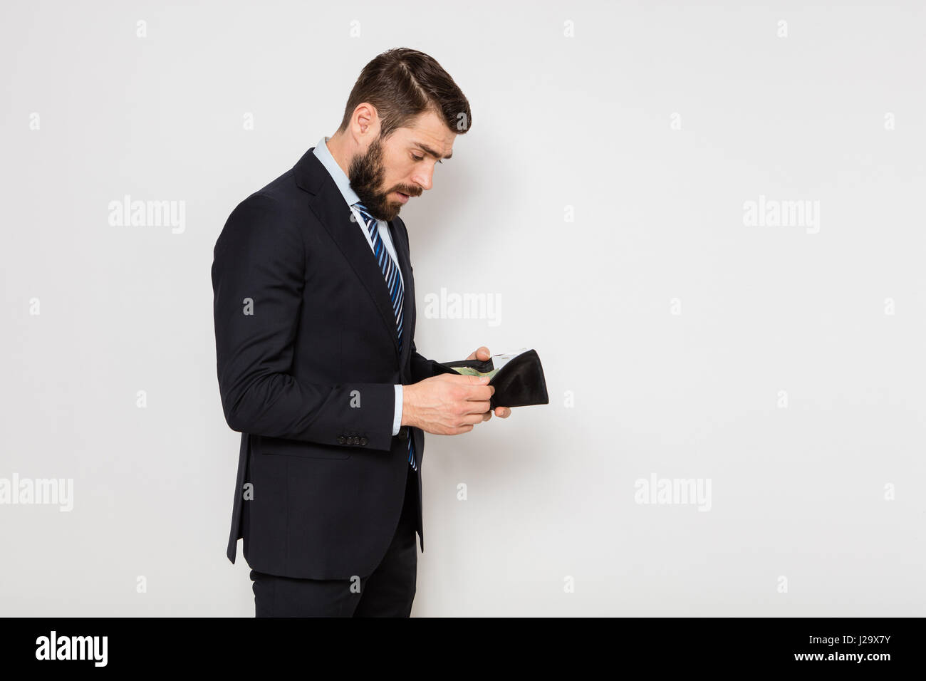 elegant man in suit standing and checking his empty wallet, on white ...