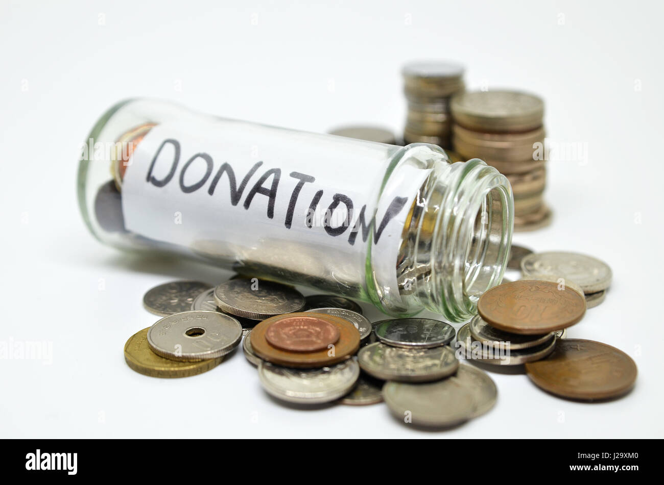 Donation lable in a glass jar with coins spilling out isolated on white ...