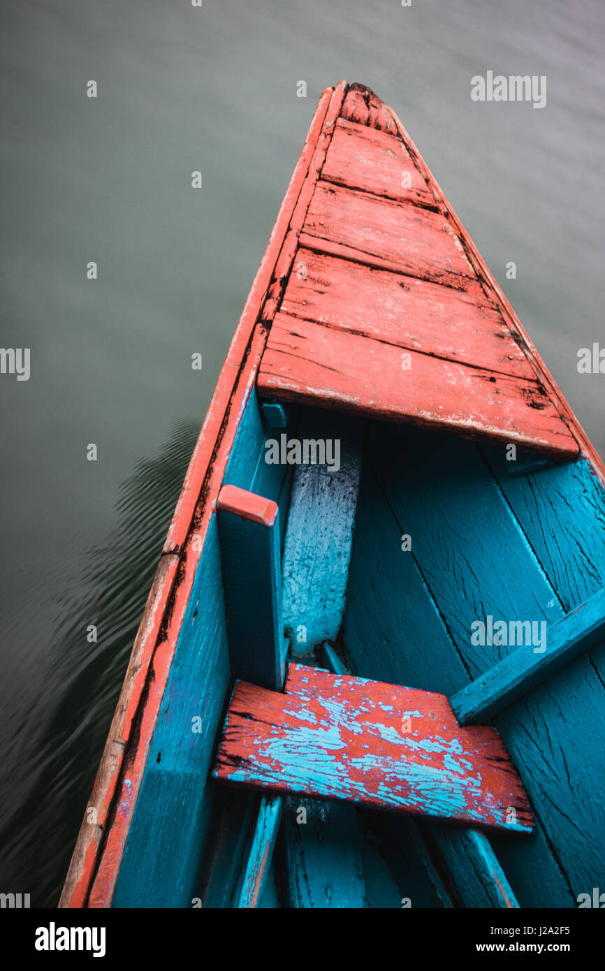 The front of a colourful wooden canoe cuts through the still water of ...