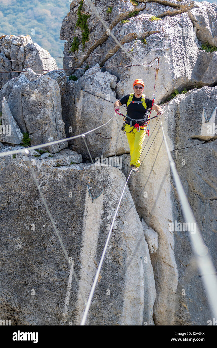 Male climber in special outfit walking rope bridge on big height Stock ...
