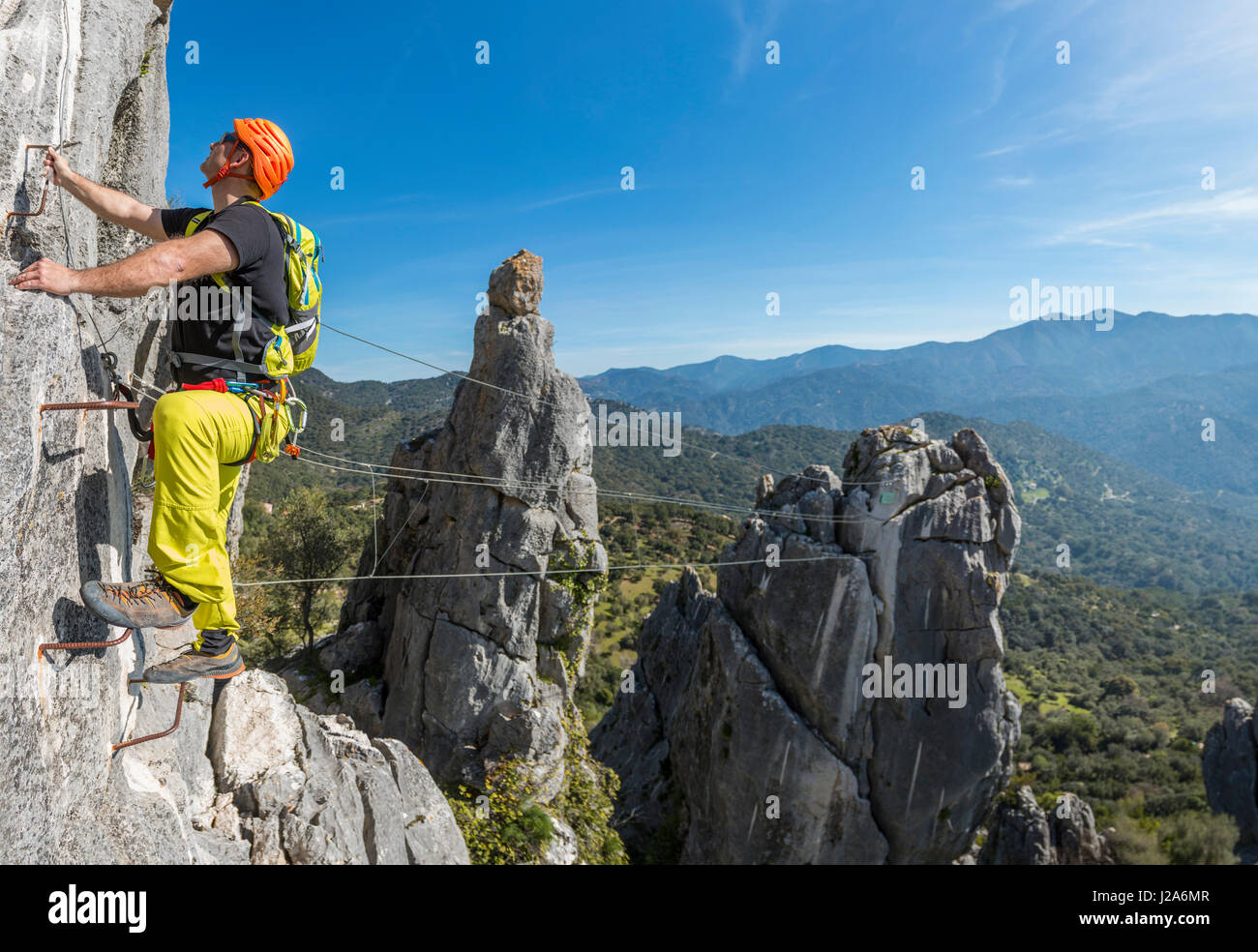 Male climber in special outfit climbing cliff with mountaineering ...