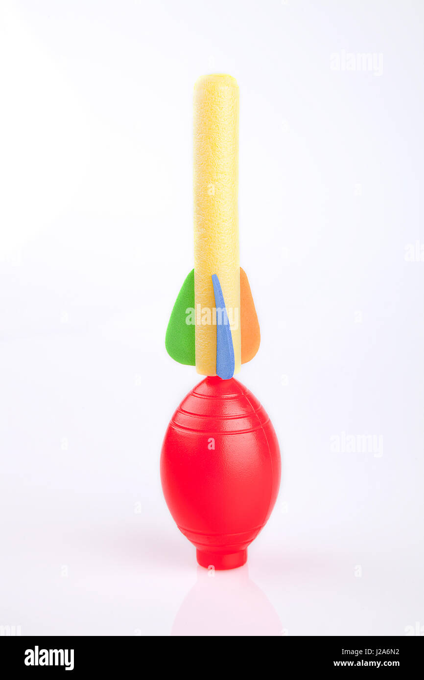 Colorful plastic rocket toy on a white surface. Plastic rocket isolated ...