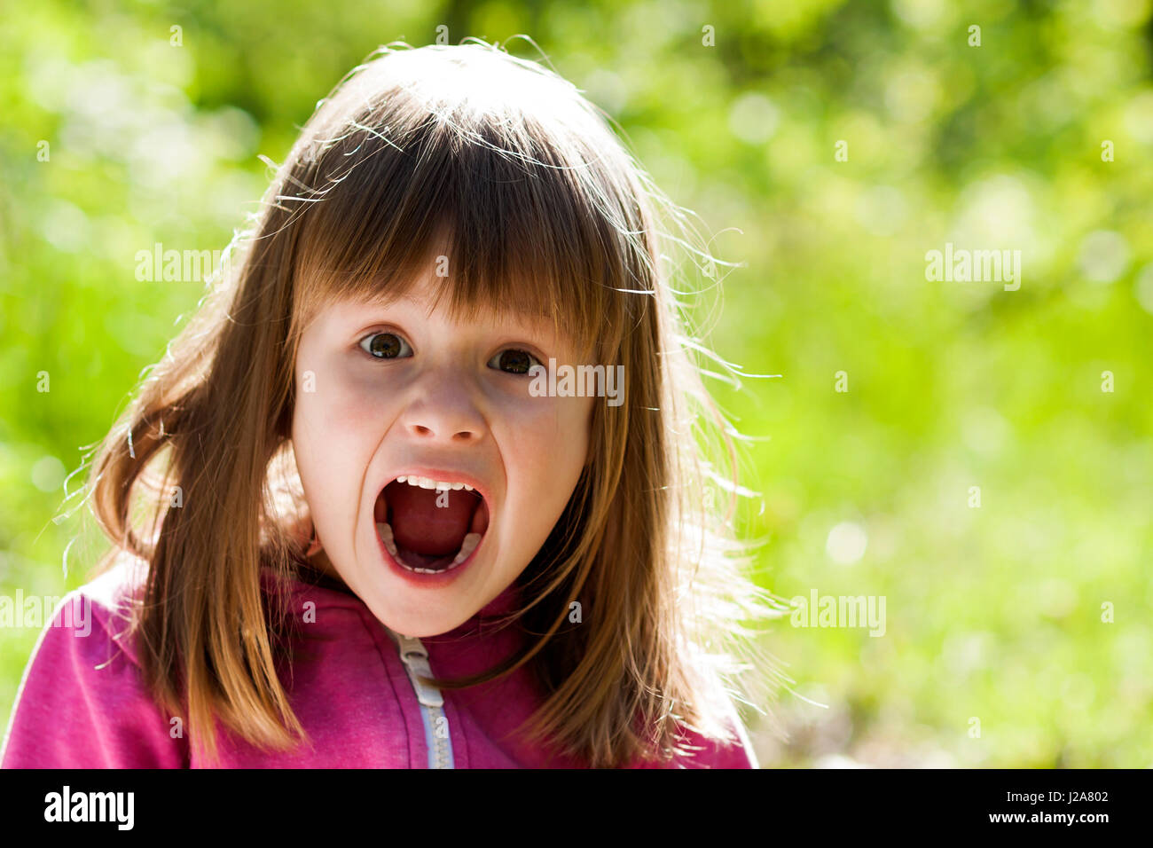 Close-up portrait of a little pretty girl with shouting face expression ...