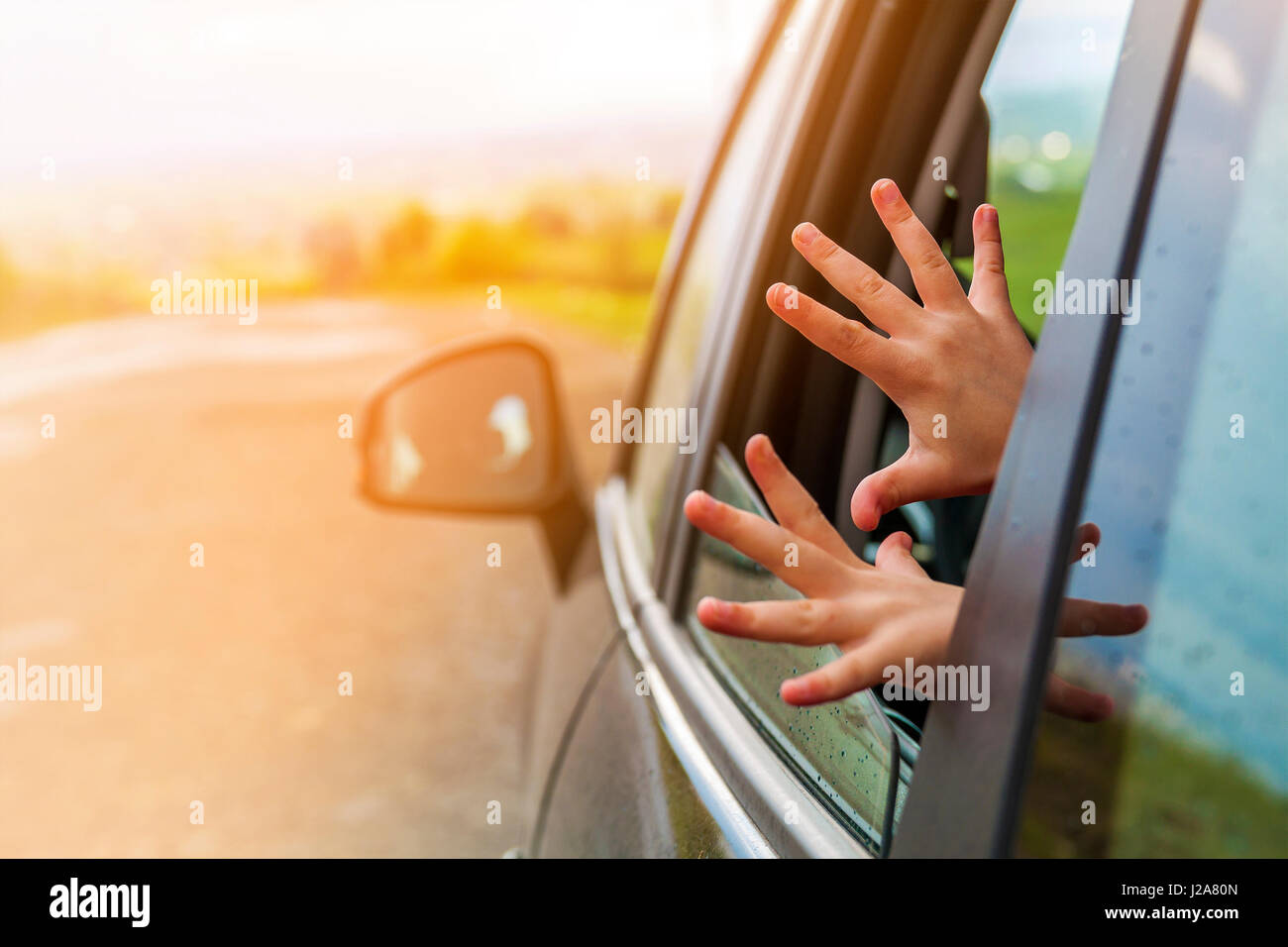 Child hands in a car window during travel to vacation. Soft light ...