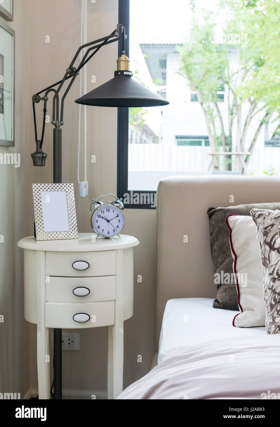 black lamp, picture frame and alarm clock on bedside table Stock Photo ...
