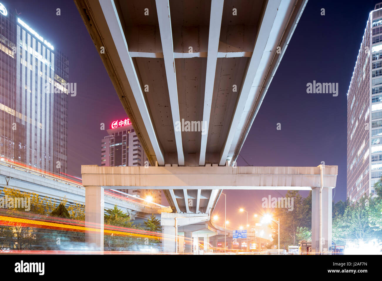 China, Beijing, Highway overpass and glowing steel and glass office ...