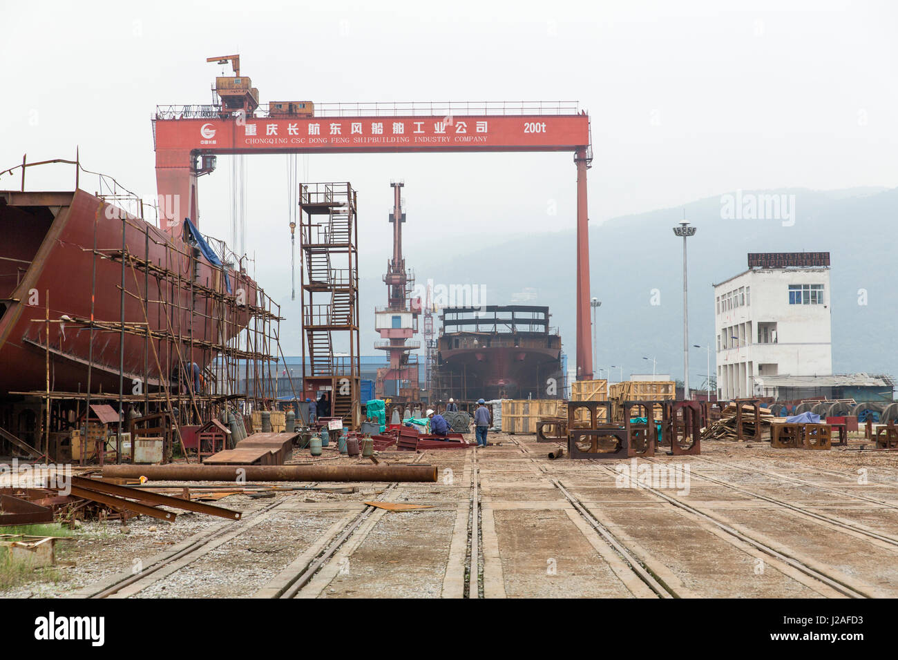 China, Chongqing, Massive crane and boat hull under construction at ...