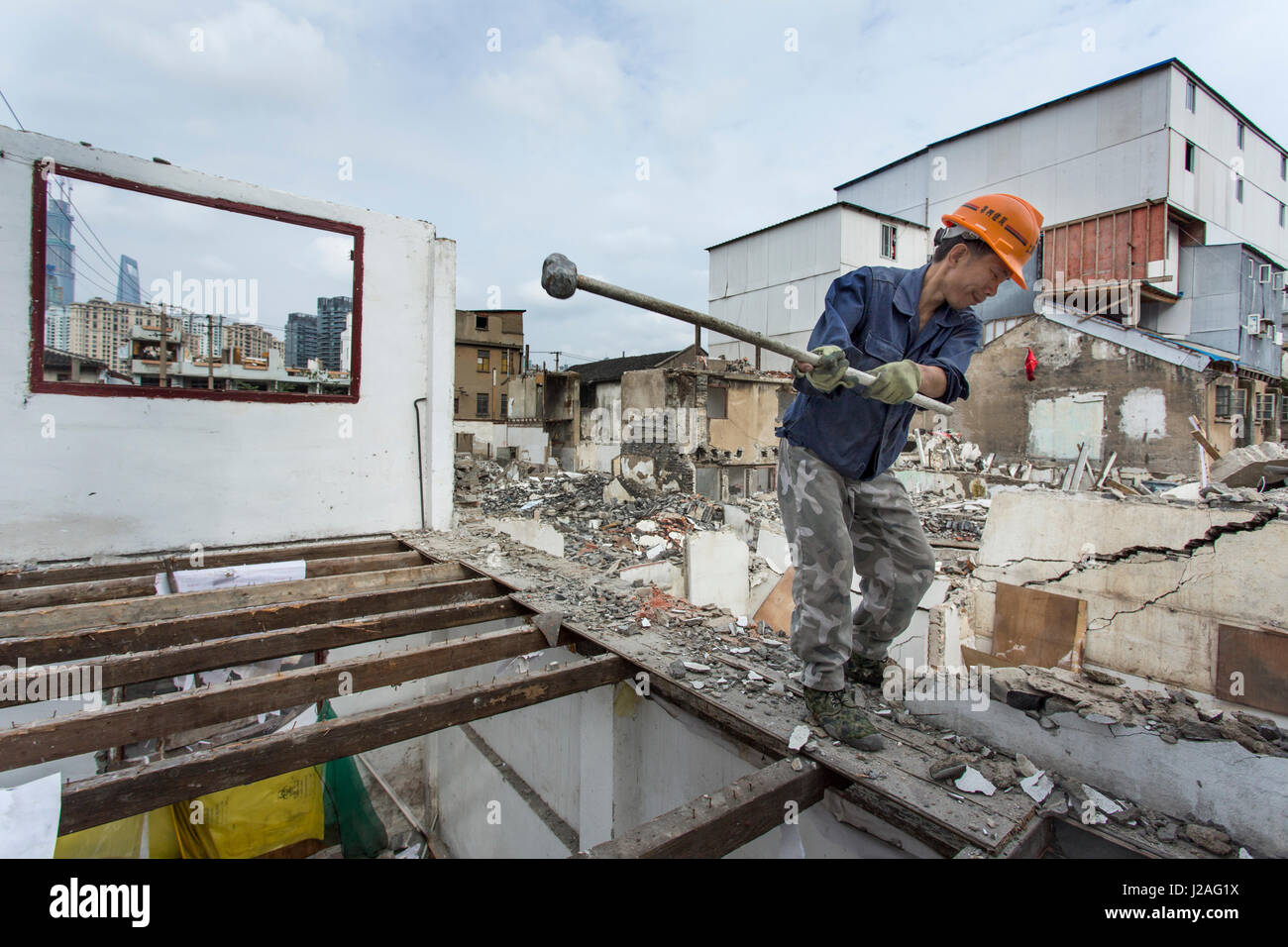 China, Shanghai, Worker uses sledge hammer to smash concrete and brick ...