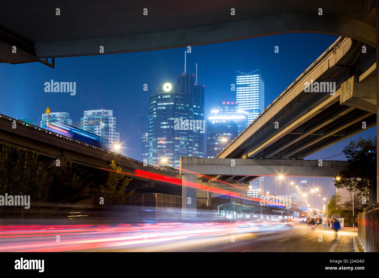 China, Beijing, Highway overpass and glowing steel and glass office ...