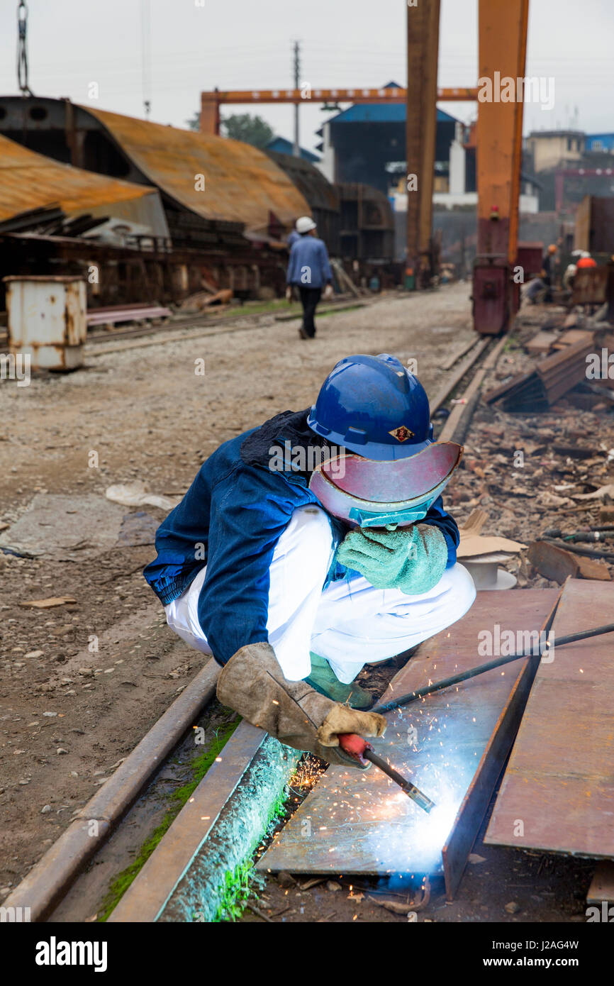China, Chongqing, Construction worker welding steel beams at sprawling ...