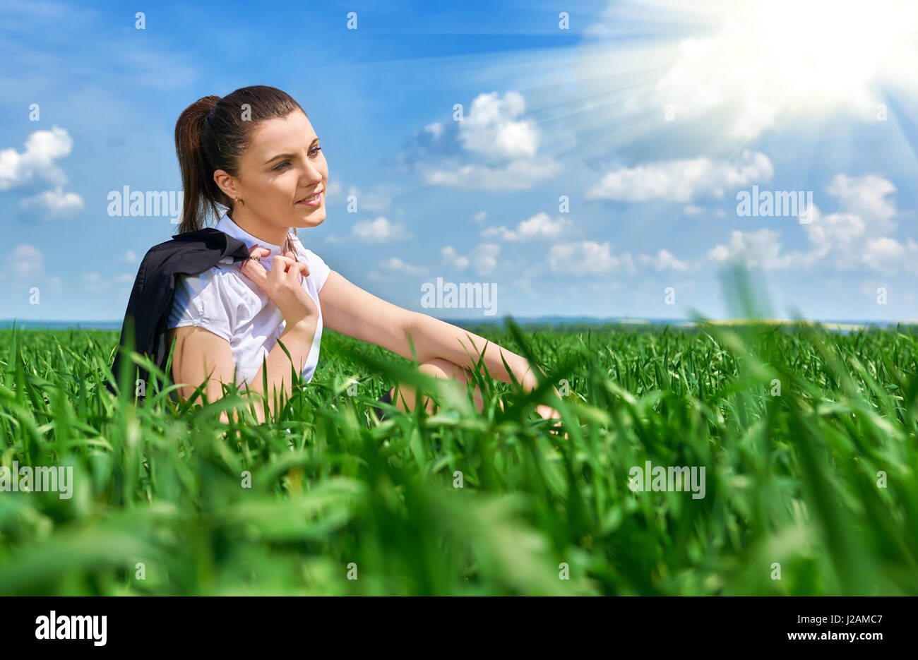 Business woman relaxing in green grass field outdoor under sun ...