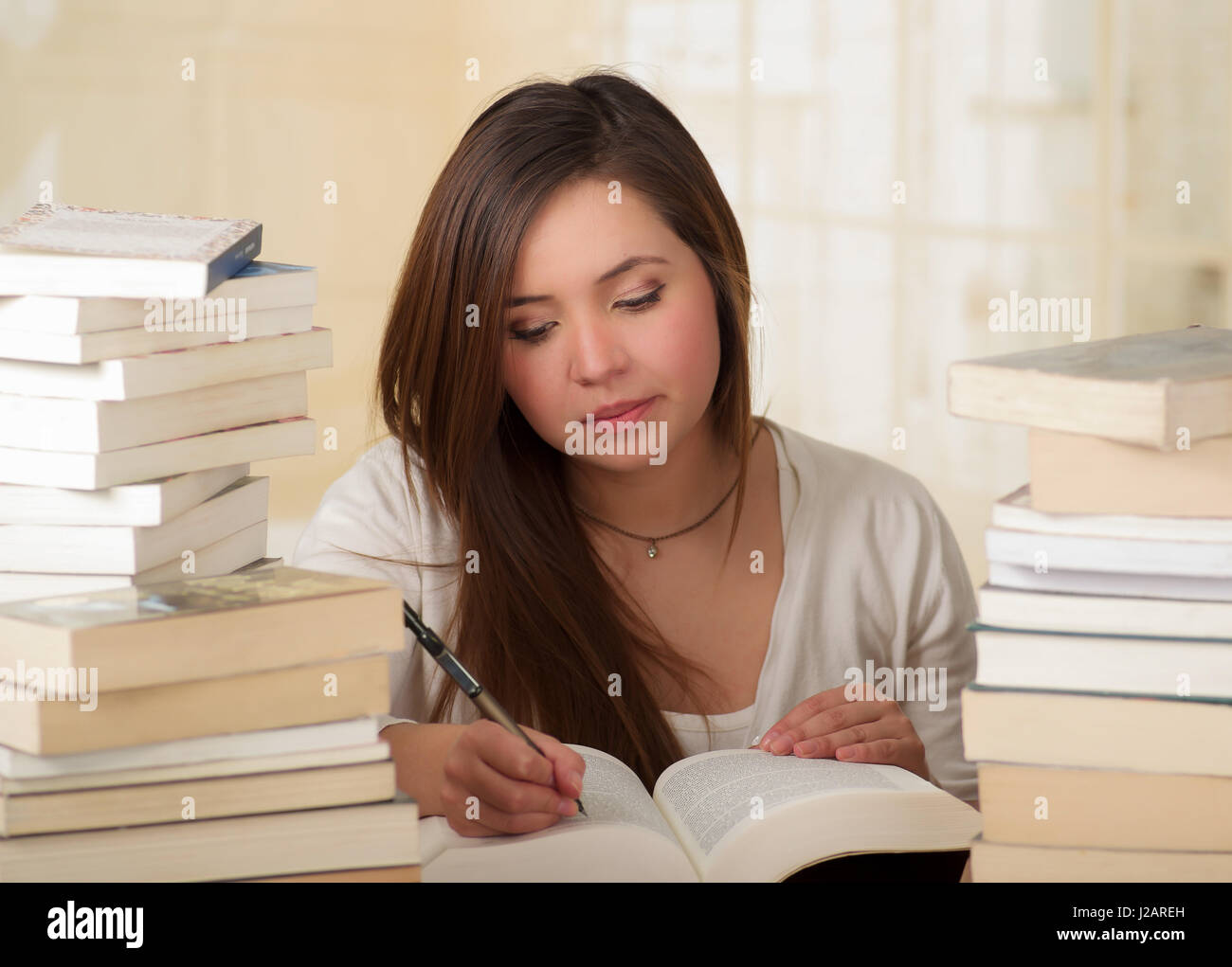 tired student girl writing and falling asleep with books in the library ...