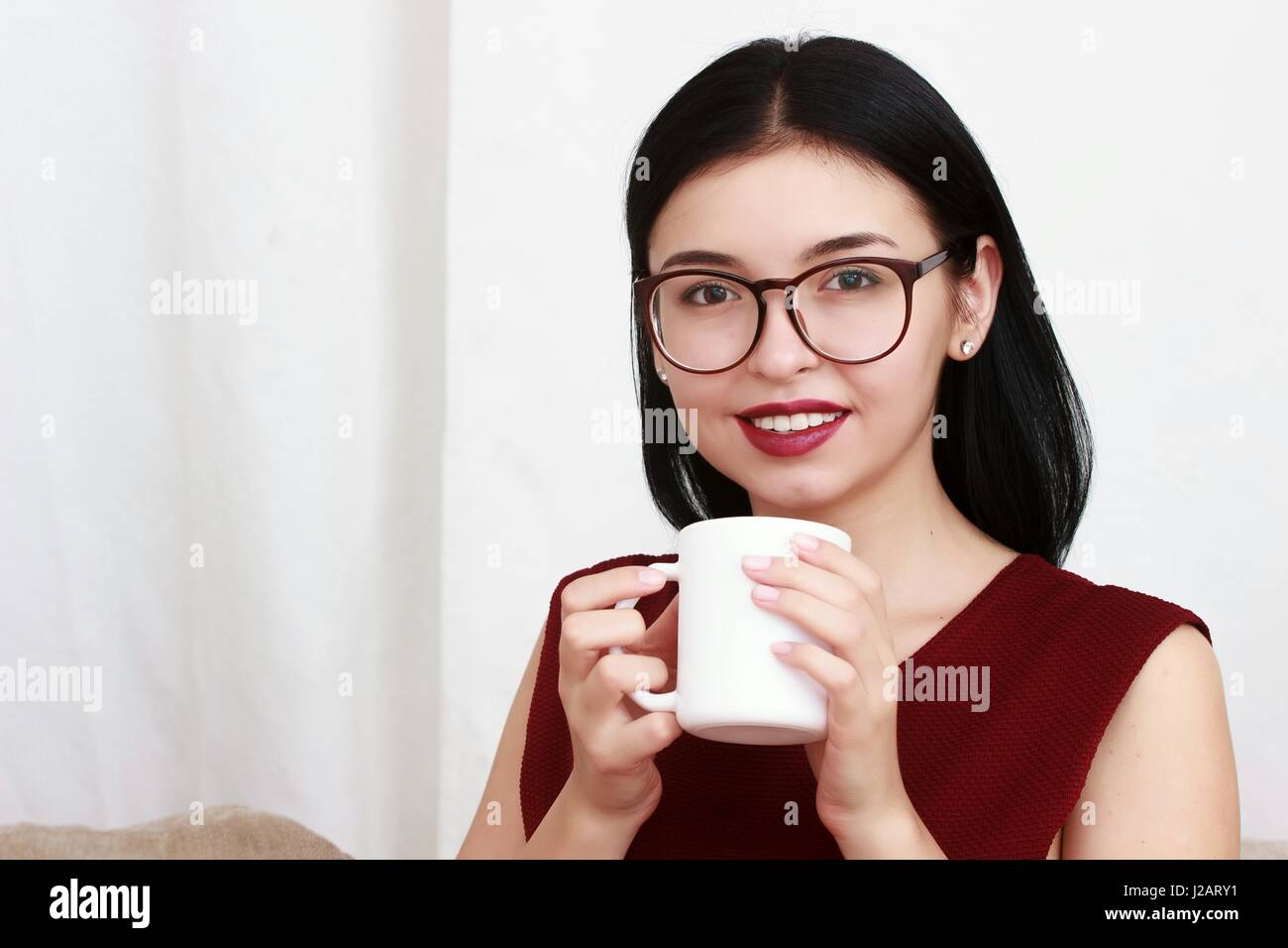 Beautiful girl in red sweater sitting on couch posing and smiling with ...