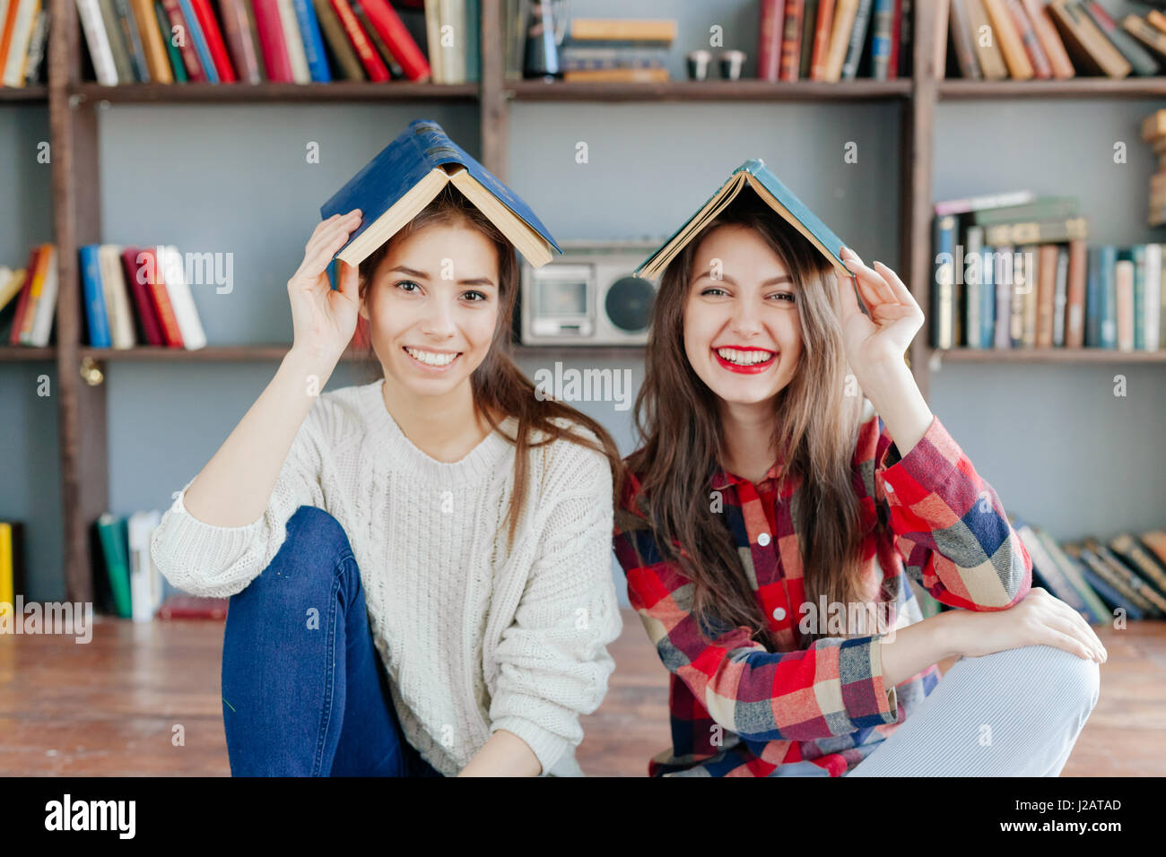 Hipster young girls hiding under the blue books Stock Photo - Alamy