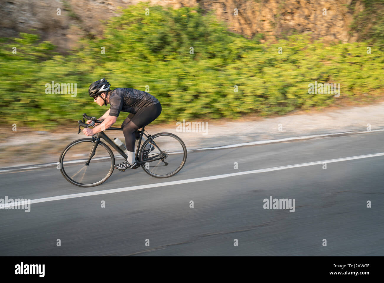 Side view of man cycling on country road Stock Photo - Alamy