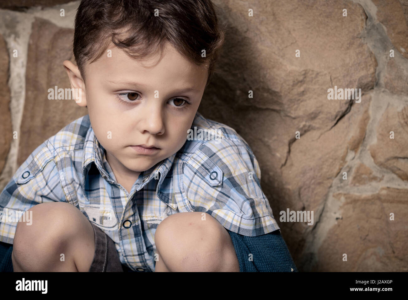 sad little boy sitting near the wall at the day time Stock Photo - Alamy