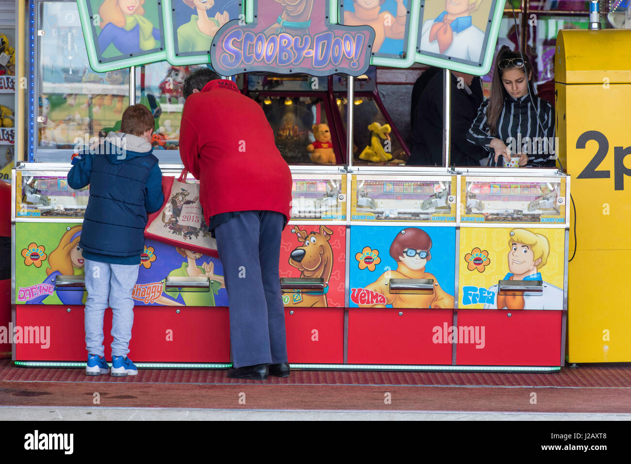 People paying an a two pence"Scooby-do' slot machine in an amusement ...