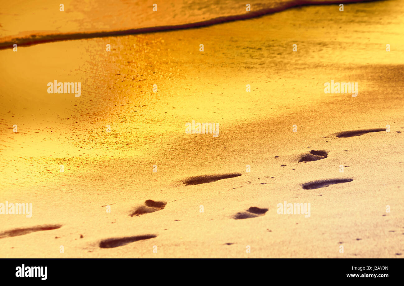 Footprints in sand at rays of sun Stock Photo - Alamy