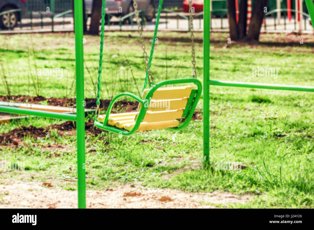 Yellow and green baby swings at playground in sunny spring day Stock ...