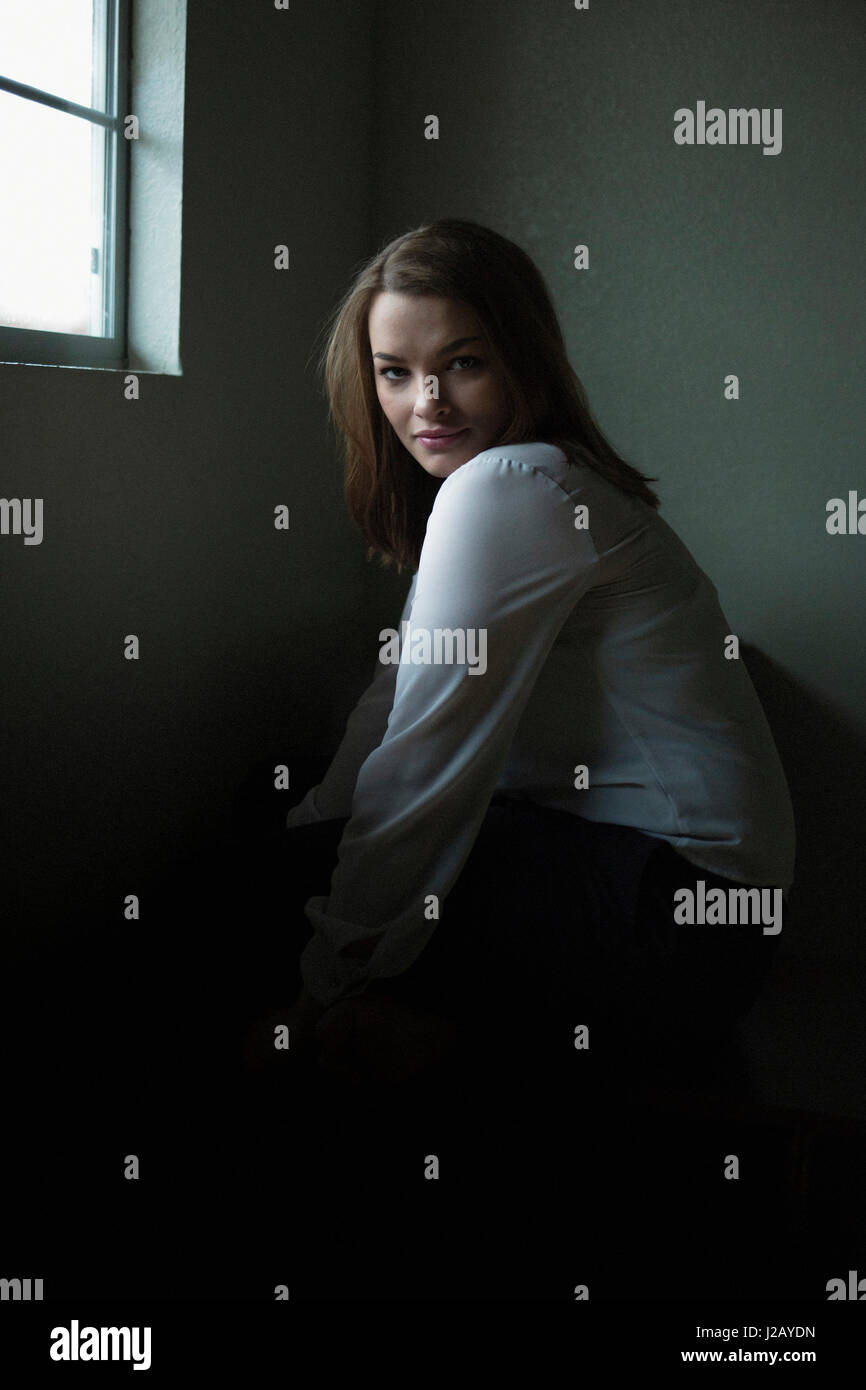 Portrait of beautiful woman sitting by window Stock Photo - Alamy
