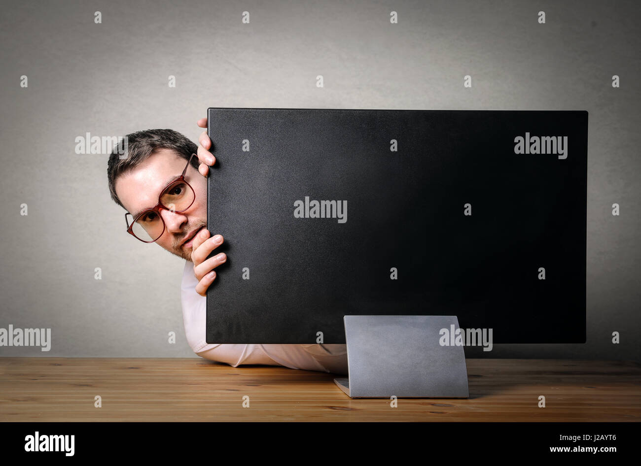 Businessman hiding behind monitor Stock Photo - Alamy
