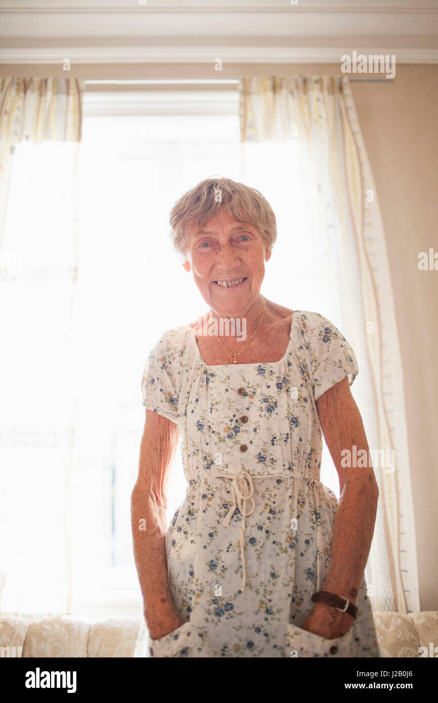 Portrait of happy senior woman sanding at brightly lit home Stock Photo ...