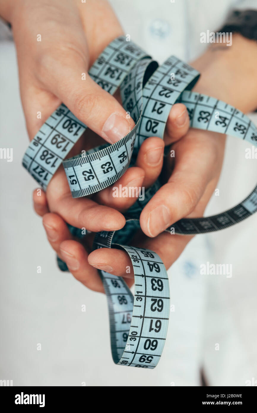 Close-up of female designer holding blue tape measure at studio Stock ...