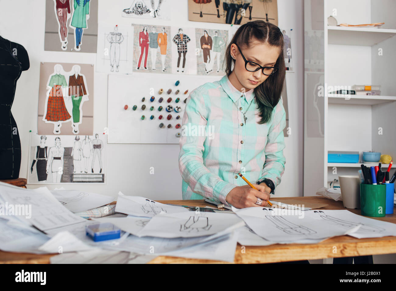 Beautiful fashion designer drawing sketch at workbench in studio Stock ...