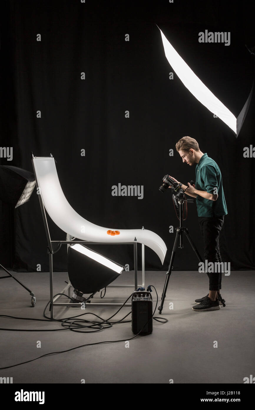 Side view of photographer photographing food on backdrop at studio ...