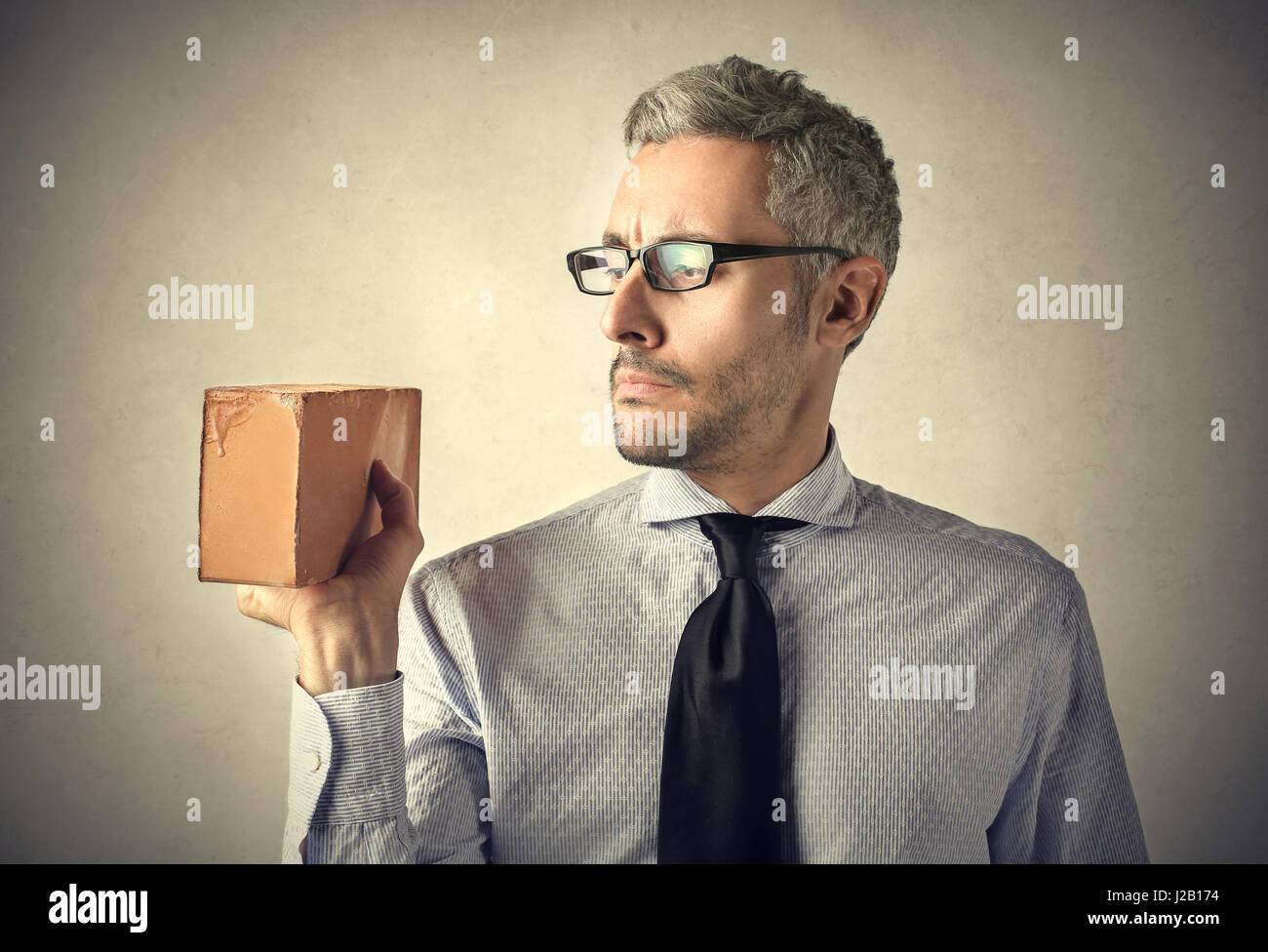 Businessman holding brick Stock Photo - Alamy