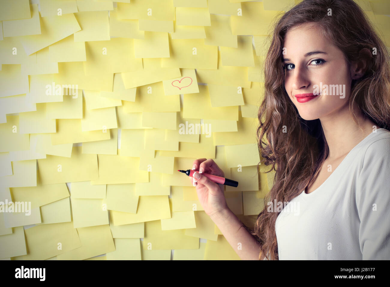 Woman drawing heart on sticky note Stock Photo - Alamy