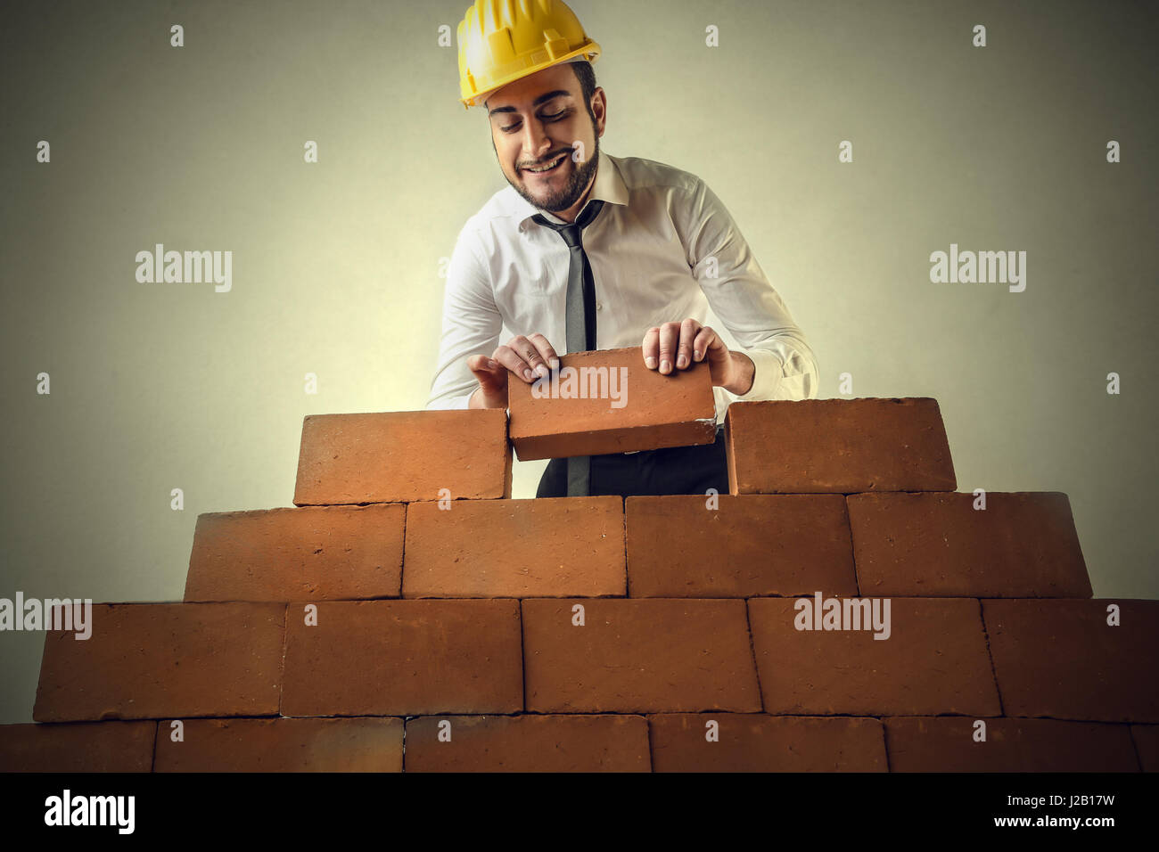 Businessman with bricks building wall Stock Photo - Alamy