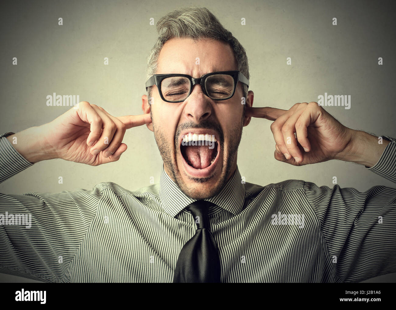 Businessman screaming and covering his ears Stock Photo - Alamy