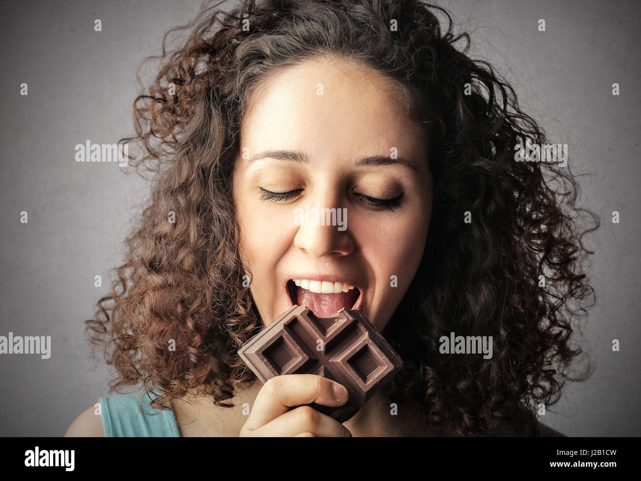 Curly woman eating chocolate Stock Photo - Alamy
