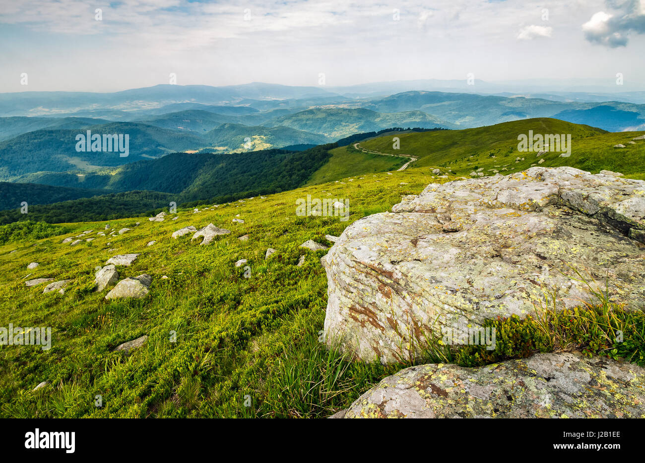 landscape with grassy meadow with giant boulders on the slope of a hill ...