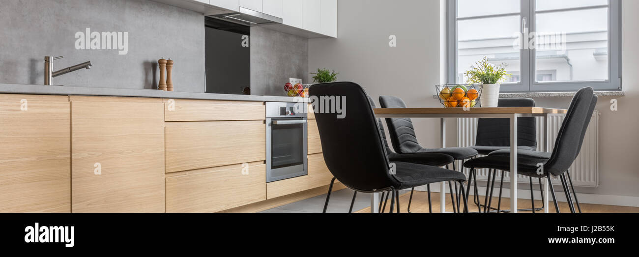 Panorama of modern kitchen with long countertop, table and chairs Stock ...