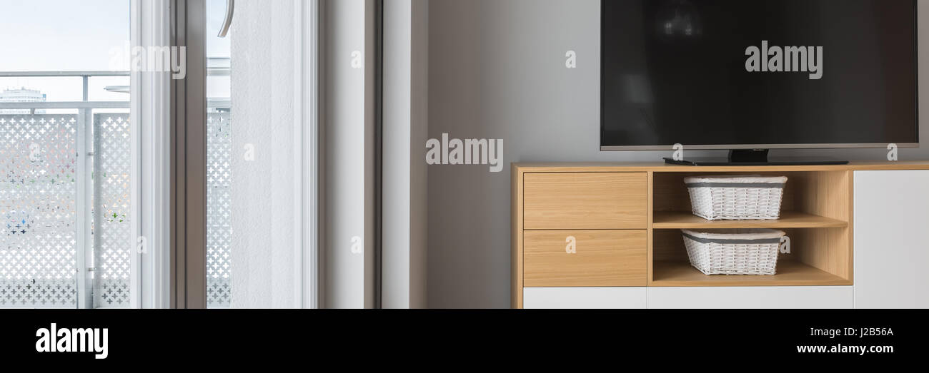 Tv in living room with balcony, grey wall and wooden cabinet, panorama ...