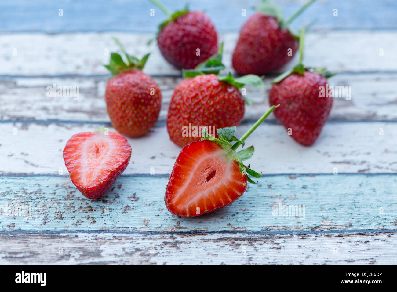 Strawberries on vintage table with one cut in half Stock Photo - Alamy