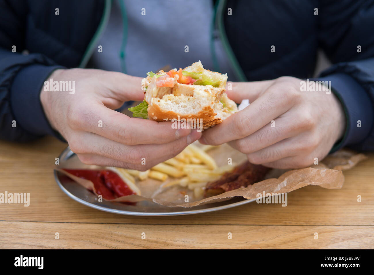 Men's hands hold a piece of bitten burger Stock Photo - Alamy