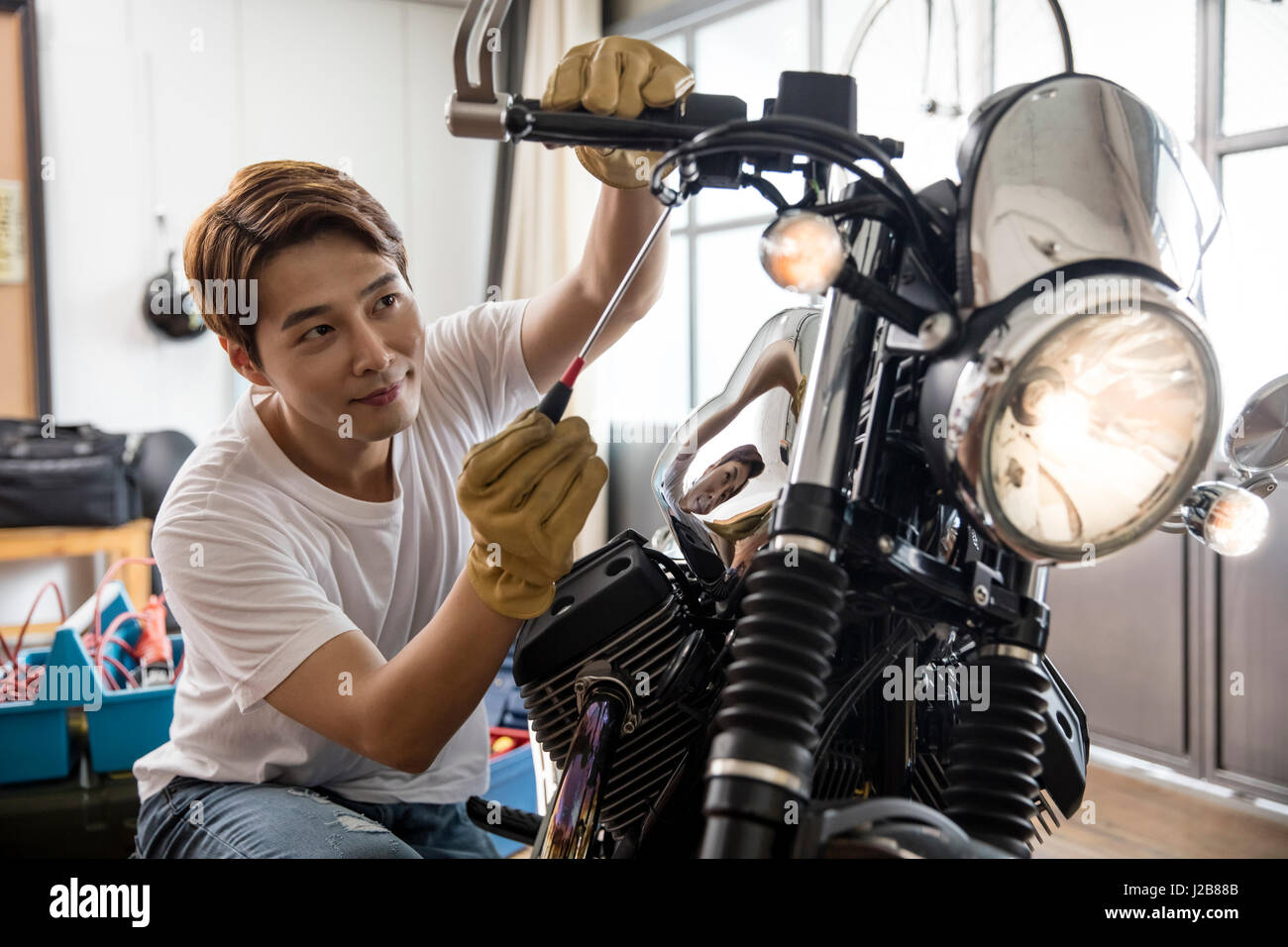 Smiling man fixing his motorcycle Stock Photo - Alamy