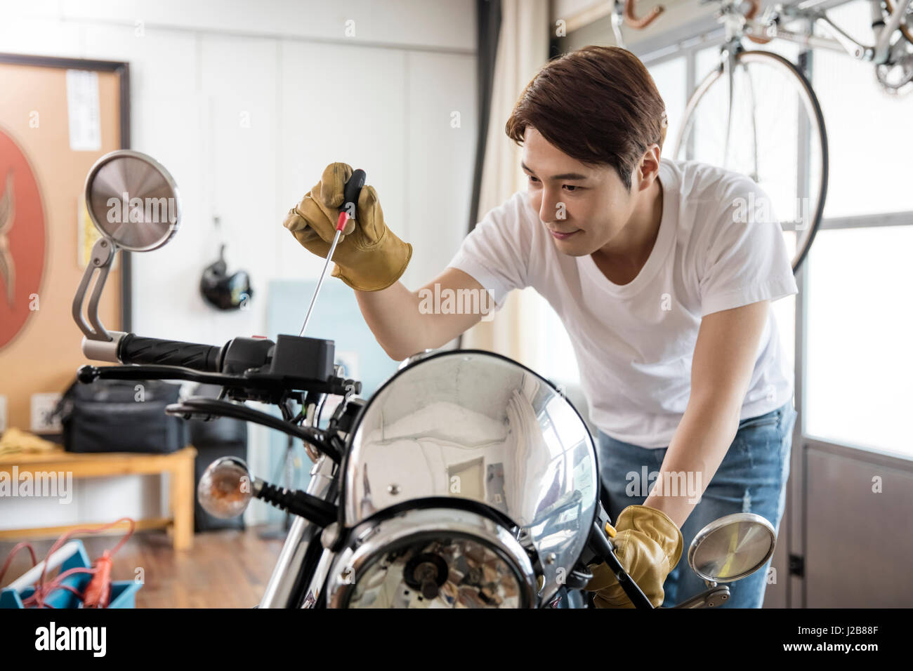 Smiling man fixing his motorcycle Stock Photo - Alamy