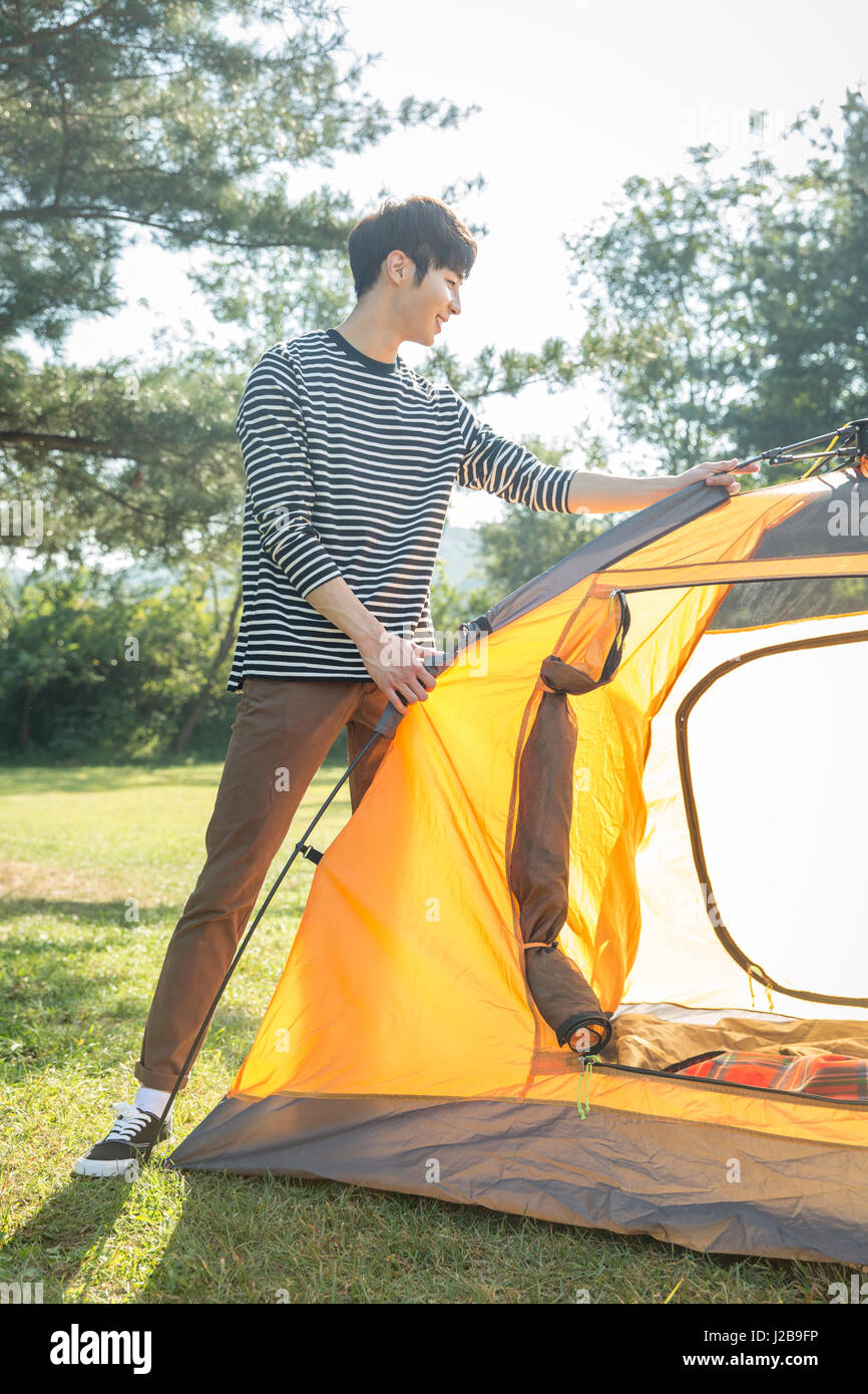 Young smiling man holding a tent Stock Photo - Alamy